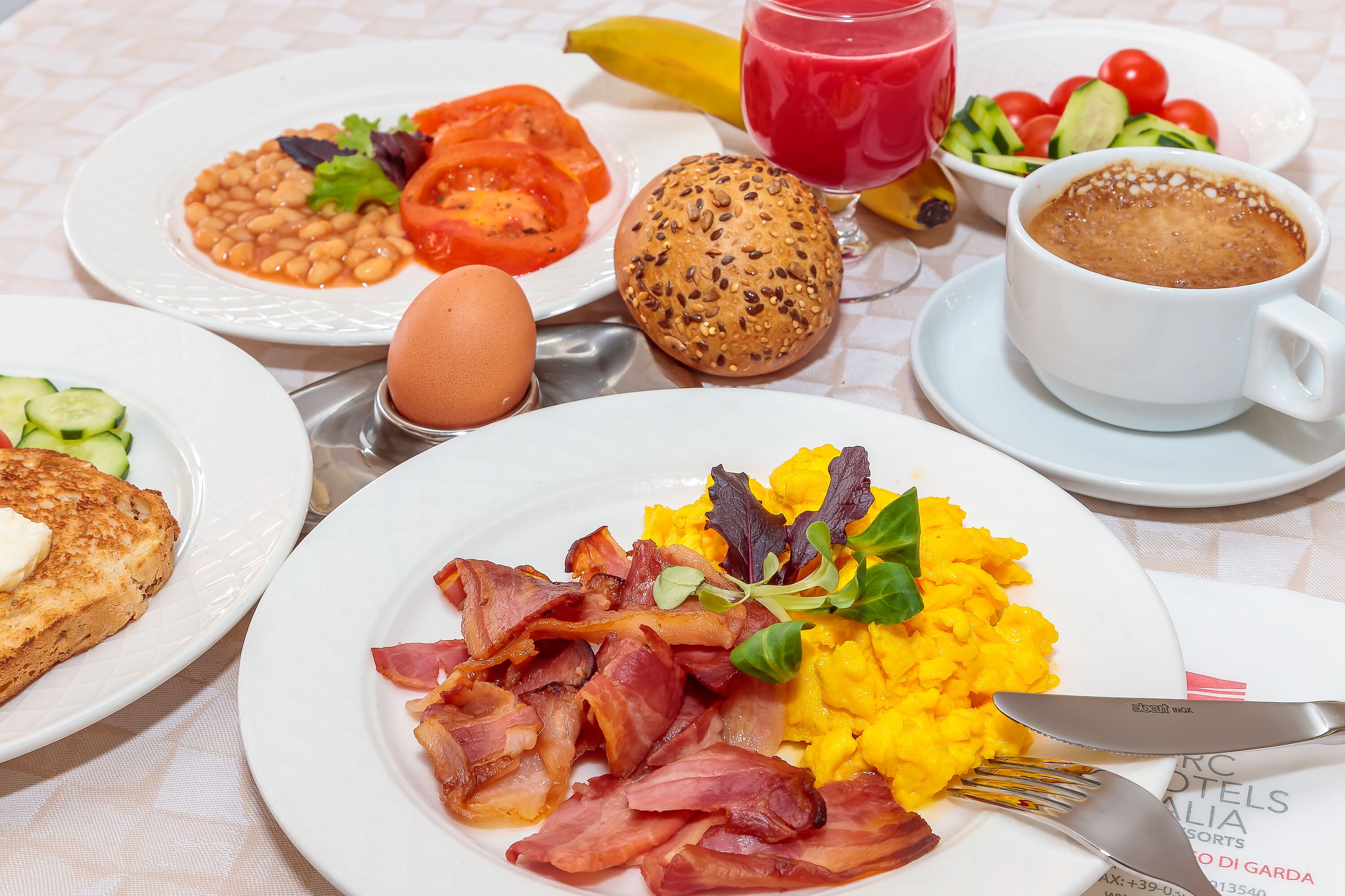 Uma mesa de café da manhã com ovos, bacon, feijão, torradas e uma salada.