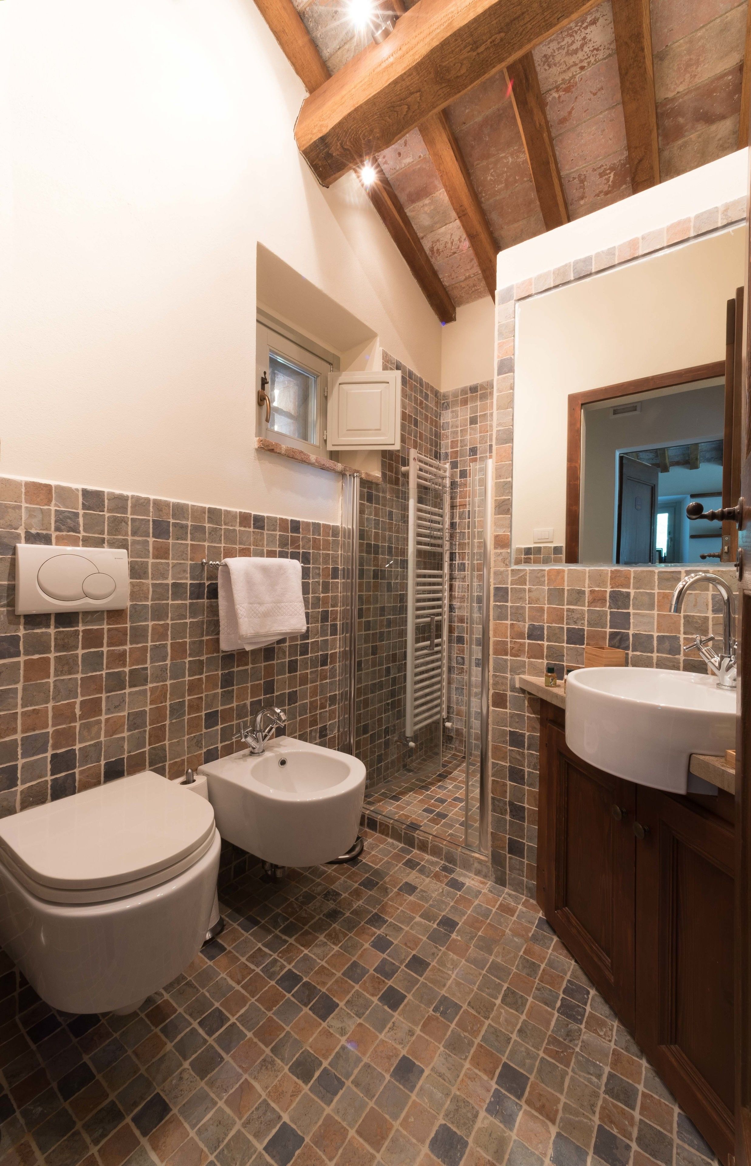 Casa de banho com chão em azulejo, sanita, lavatório e área de duche.