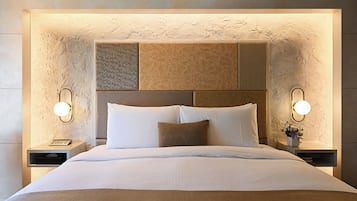 Quarto de hotel com uma cama grande, duas mesinhas de cabeceira e parede com textura.