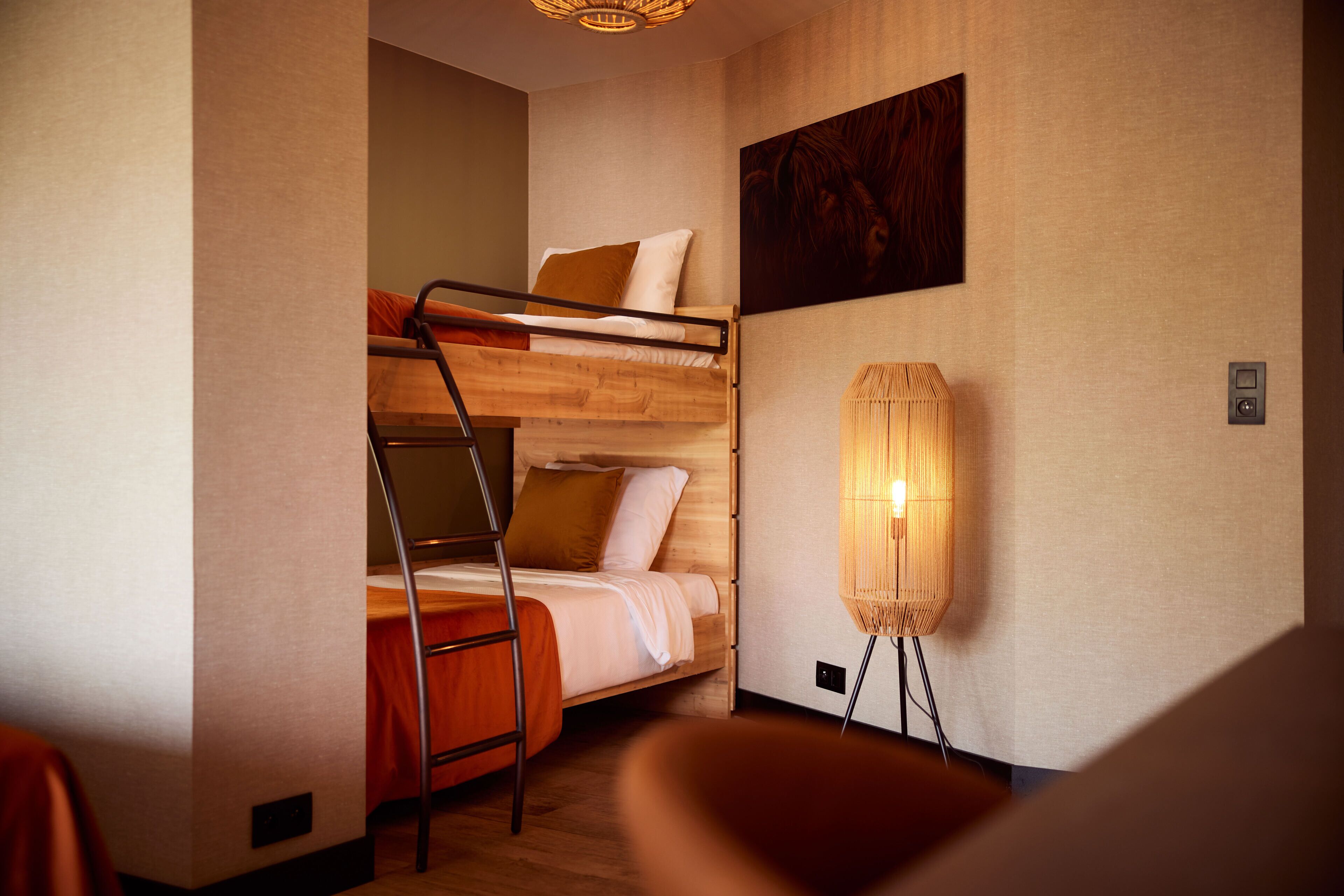 Quarto com beliche, luminária de pé e quadro na parede.