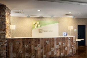 Uma mesa de recepção com parede de pedra, painéis de madeira e uma placa indicando 'Holiday Inn'.