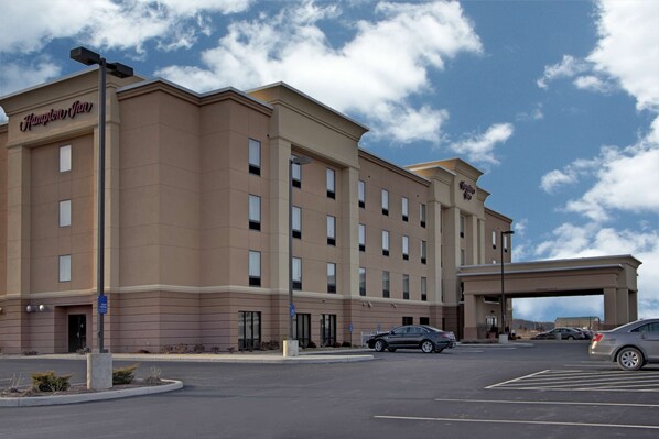 Um hotel Hampton Inn com design moderno, vários andares e estacionamento.