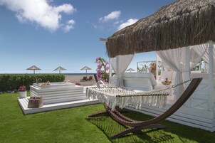 Uma área de estar à beira-mar, com espreguiçadeiras, sofás e piscina.
