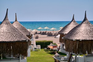 Resort à beira-mar com cabanas de palha, espreguiçadeiras e guarda-sóis.