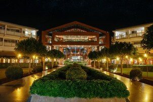 Um hotel moderno com um átrio central, vários andares e uma entrada bem iluminada.