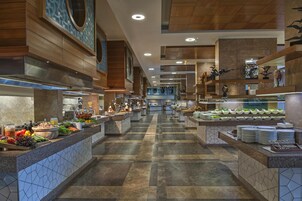 Ampla área de buffet com diversas estações de comida e um corredor central.