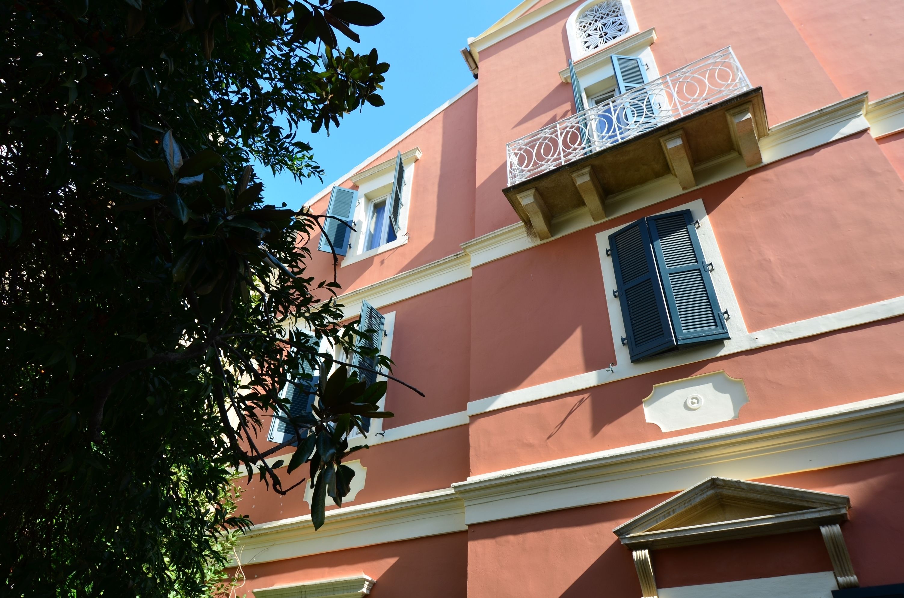 Um edifício de vários andares com varandas, persianas e uma janela com unidade de ar condicionado.