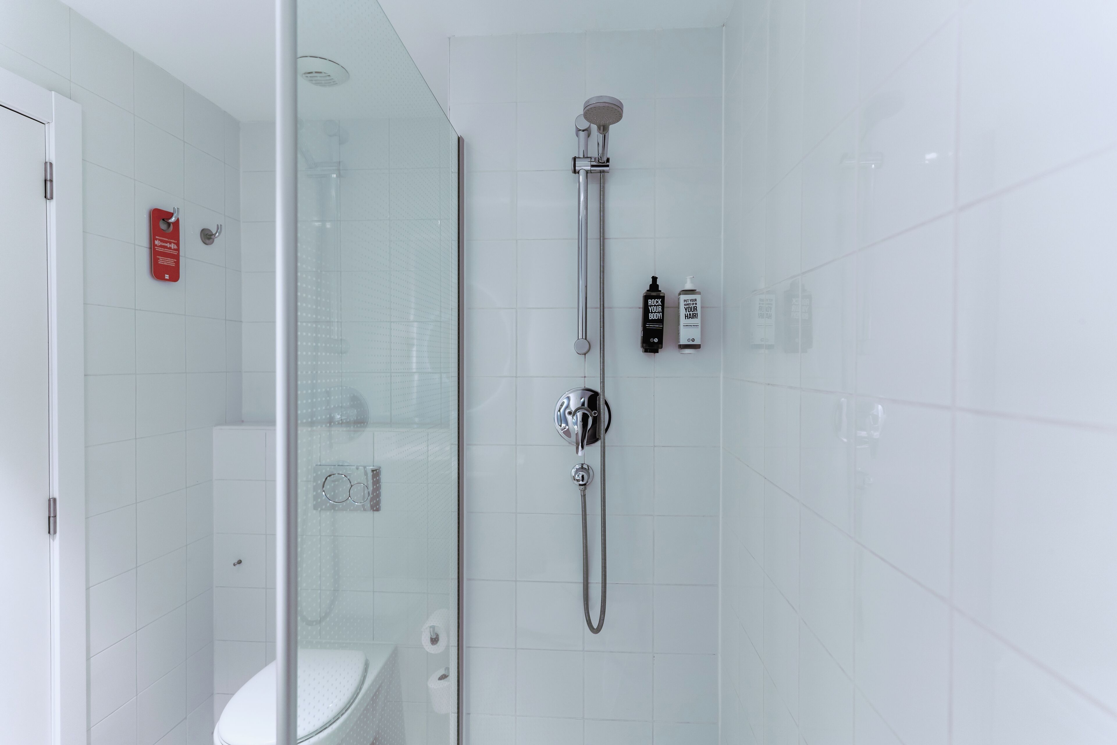 Um banheiro moderno com box de vidro, vaso sanitário e secador de mãos.