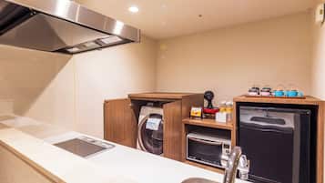 Uma cozinha compacta equipada com máquina de lavar e secar integradas, micro-ondas e frigorífico.