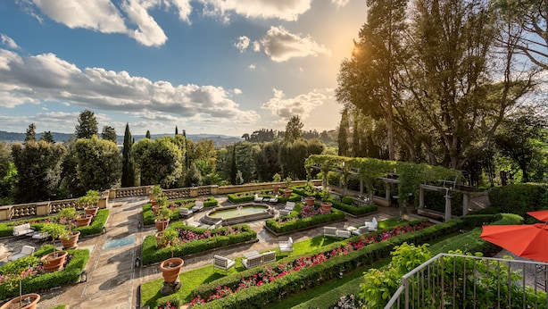 Um jardim formal com uma fonte, áreas de estar e vista para a paisagem.