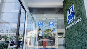 Entrada de hotel com portas de vidro, uma placa com a inscrição "LP HOTELES" e uma parede verde.