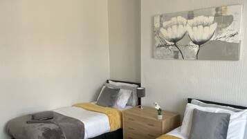 Quarto de hotel com duas camas, uma mesa de cabeceira, um abajur e um quadro na parede.