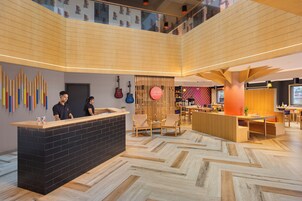 Uma área de recepção moderna, com um balcão preto, cadeiras de madeira e um chão com padrão herringbone.
