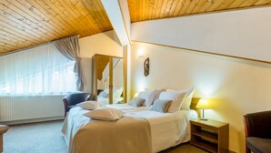 Quarto com cama, mesa de cabeceira, luminária, cadeira e janela com cortinas.