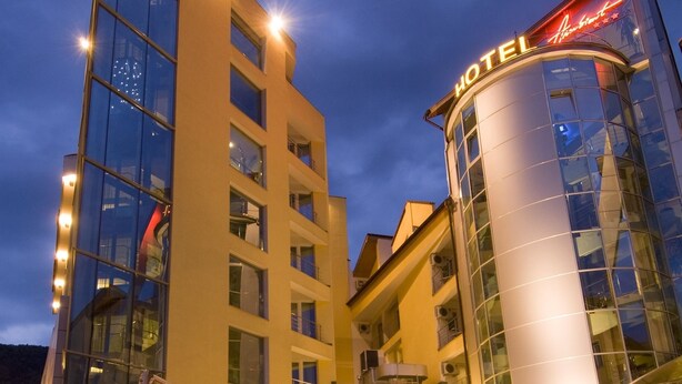 Um hotel moderno com fachada de vidro, uma placa chamativa com a palavra 
