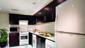 Uma cozinha moderna com armários escuros, micro-ondas, forno, lava-louças e frigorífico.