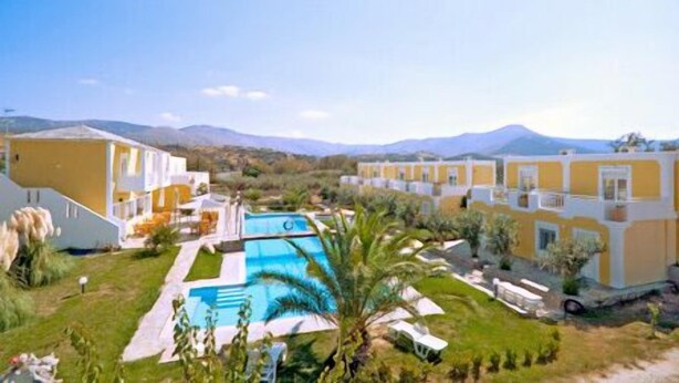 Resort com vários edifícios, uma piscina central e um cenário montanhoso.