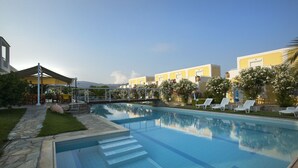 Piscina com espreguiçadeiras, um alpendre coberto e um caminho de pedra.