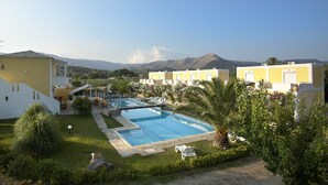 Um resort com piscina, área de estar externa e montanhas ao fundo.