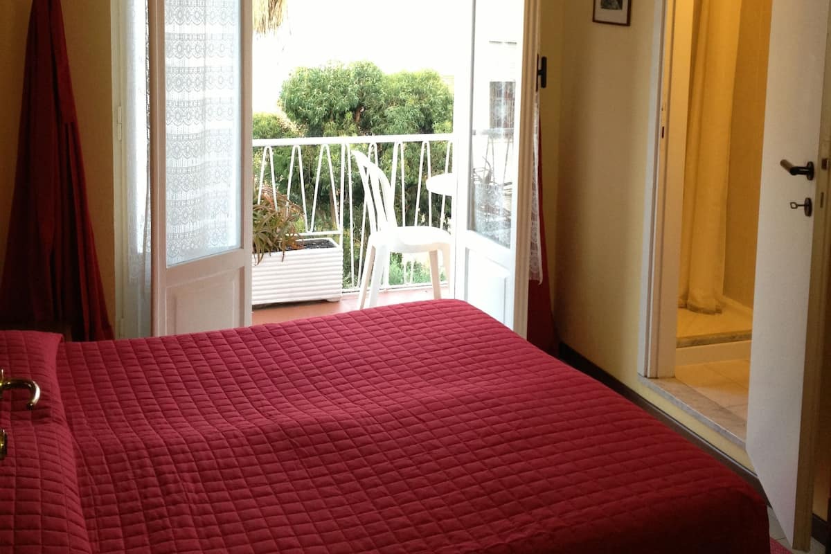 Um quarto com uma cama, uma porta que dá para uma varanda e um ventilador de teto.