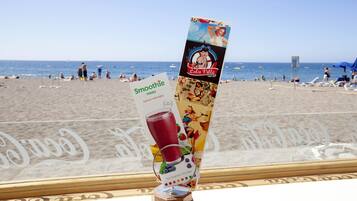 Vista da praia com um suporte de menu exibindo um smoothie e uma bebida.