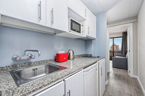 Cozinha moderna com pia de aço inoxidável, torradeira vermelha e micro-ondas.