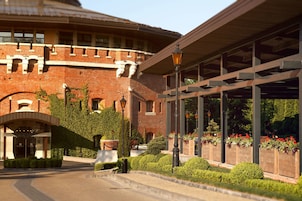 Um edifício de tijolos com entrada coberta e área de jardim ajardinado.