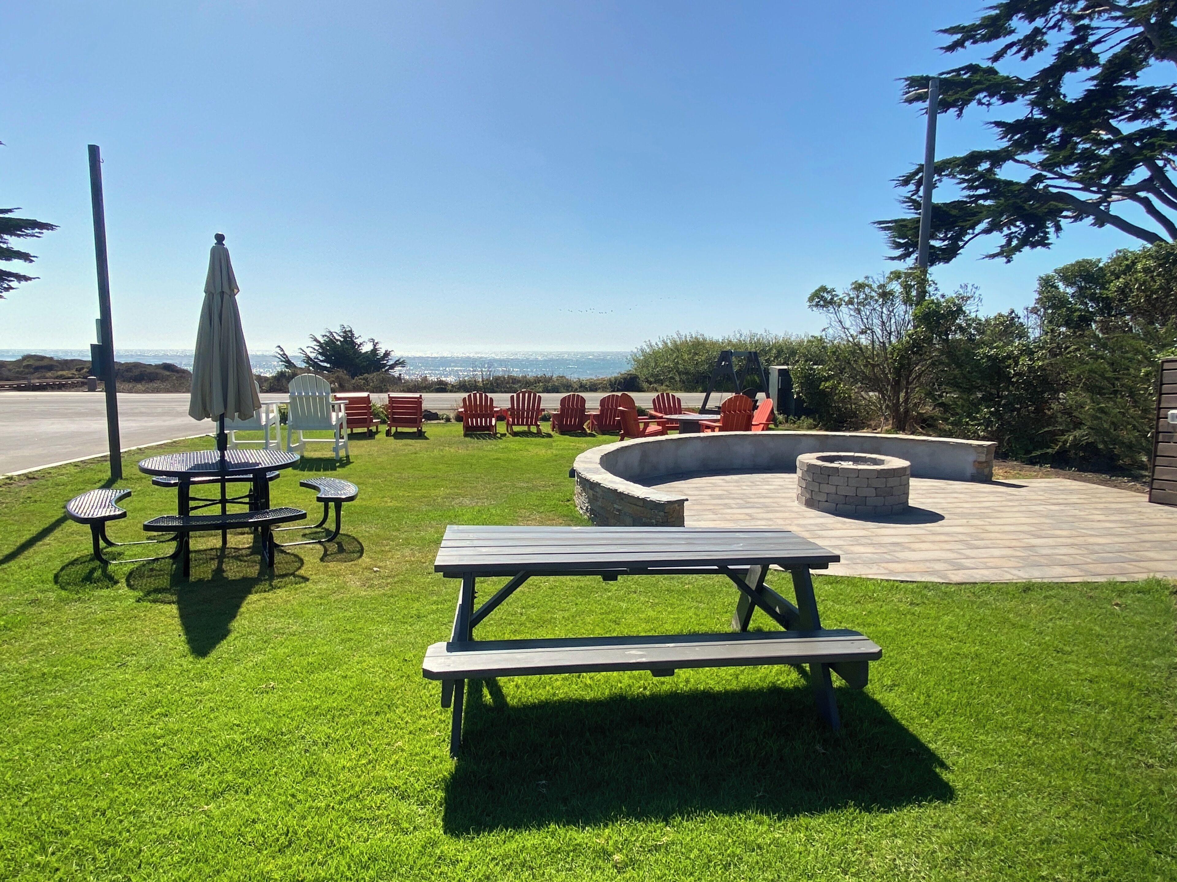 Área de pátio com mesa para piquenique, cadeiras de exterior e lareira.