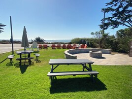 Área de pátio com mesa para piquenique, cadeiras de exterior e lareira.