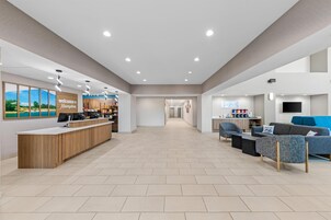 Um hall amplo com balcão de recepção, área de estar e cozinha compacta.