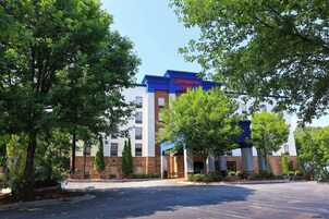 Um Hampton Inn com fachada de tijolos, janelas amplas e estacionamento.
