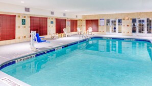 Piscina interior com água cristalina, níveis de profundidade indicados e persianas de segurança vermelhas nas paredes.