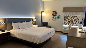 Quarto de hotel com uma cama grande, mesas de cabeceira, uma escrivaninha e uma cadeira.