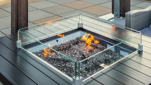 Um terraço no telhado com lareira de vidro, pérgola de madeira e luzes de Natal.