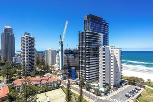 Paisagem costeira urbana com edifícios altos, uma praia e uma grua de construção.