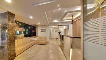 Um hall moderno com piso de mármore, um sofá bege e uma mesa de recepção.