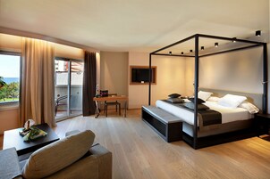 Quarto de hotel moderno com cama de dossel, escrivaninha com cadeira, sofá e varanda com cortinas.