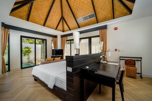 Quarto de hotel moderno com uma cama grande, uma escrivaninha e uma televisão.