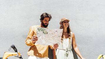 Duas pessoas segurando um mapa, ao lado de uma bicicleta amarela.