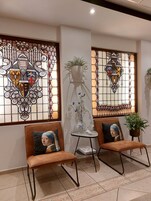 Quarto com duas cadeiras, uma mesa pequena e um vitral decorativo.
