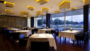 Um restaurante moderno com várias mesas, grandes janelas e vista para uma paisagem nevada.