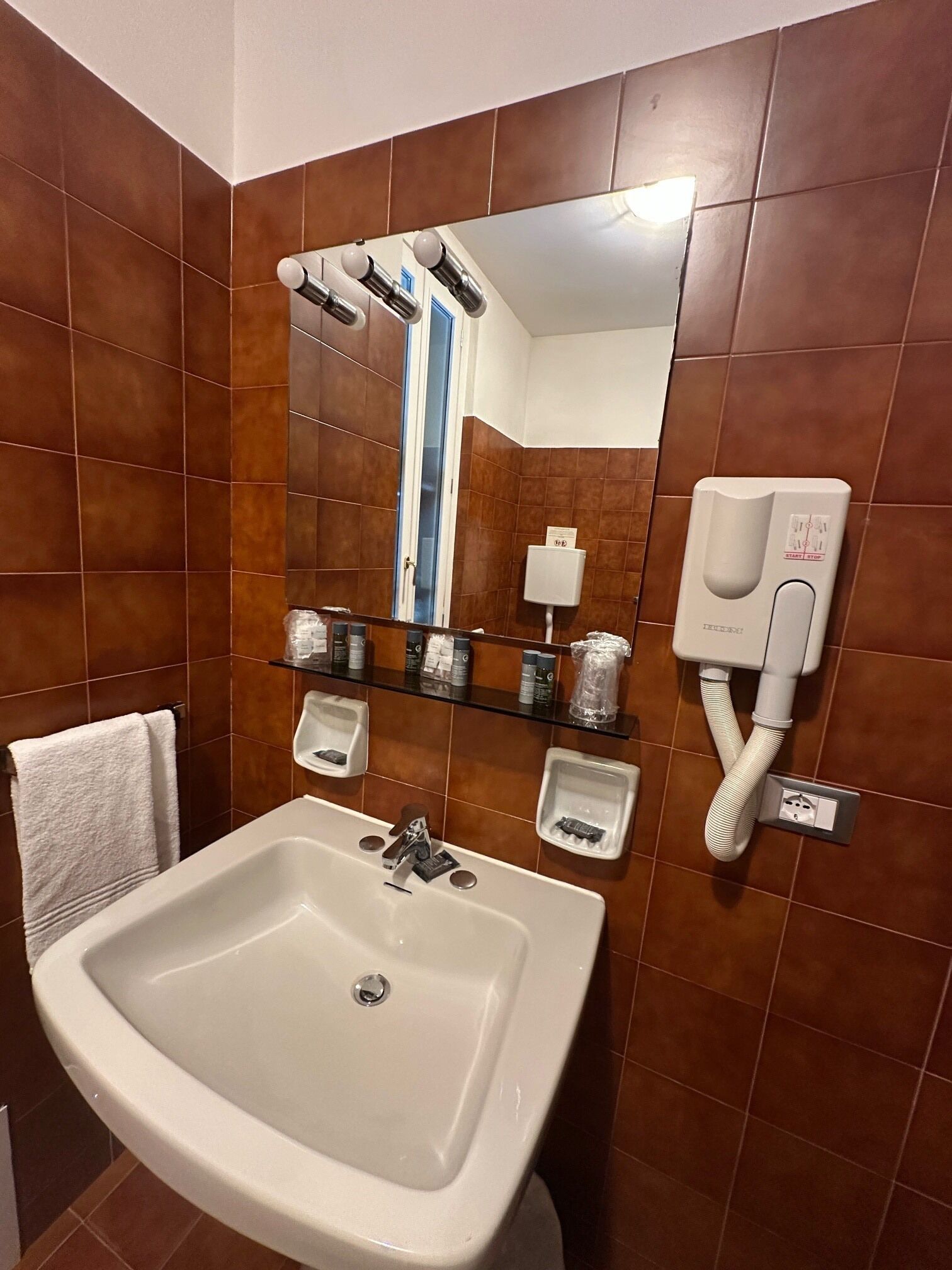 Casa de banho com lavatório, espelho, porta-toalhas e artigos de higiene pessoal.