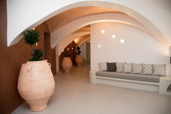 Um interior moderno com um banco branco curvo, grandes vasos de terracota e um design minimalista.