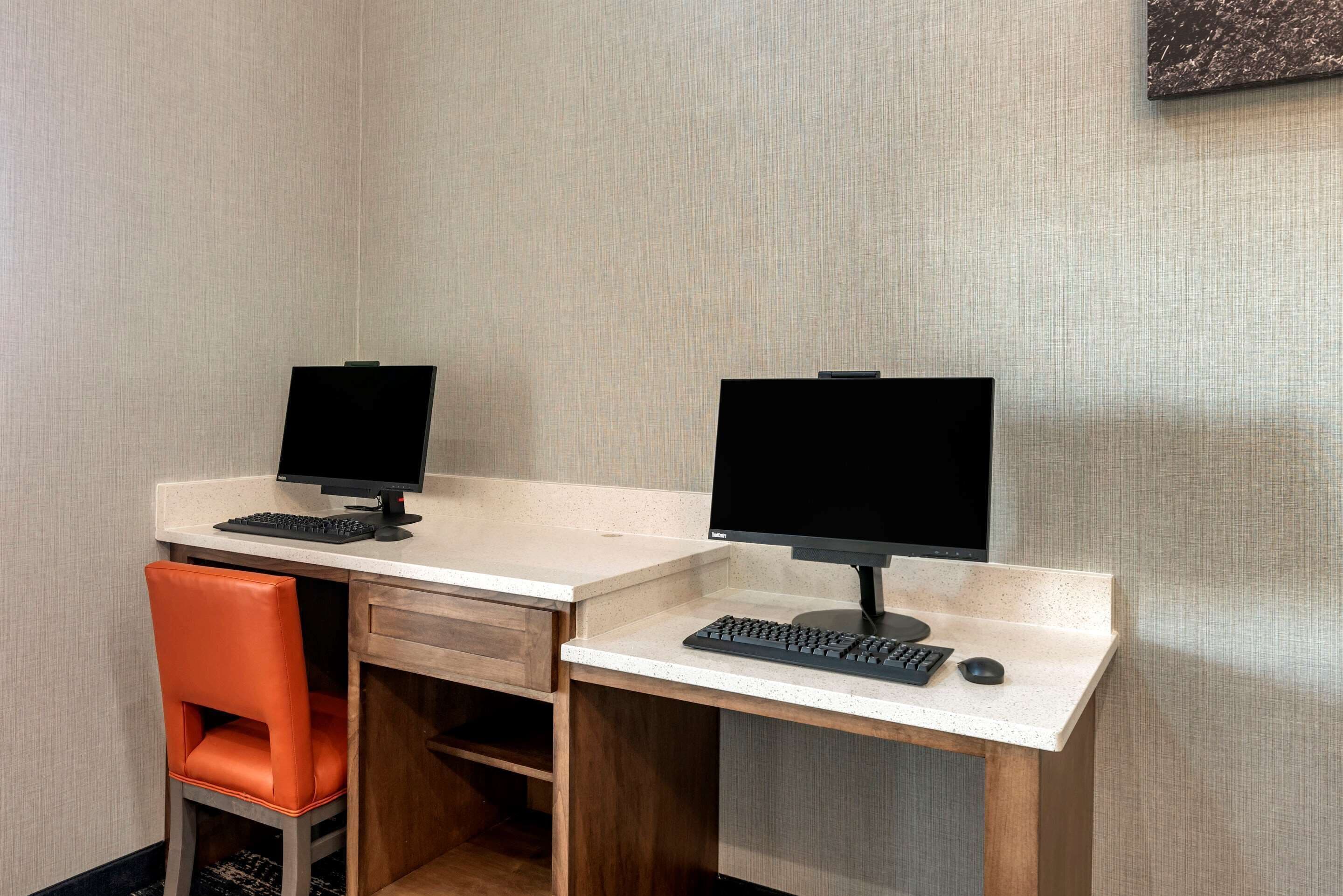 Um espaço de trabalho com duas mesas, cada uma com monitor de computador, teclado e rato.