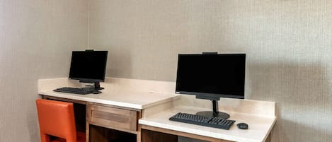 Um espaço de trabalho com duas mesas, cada uma com monitor de computador, teclado e rato.