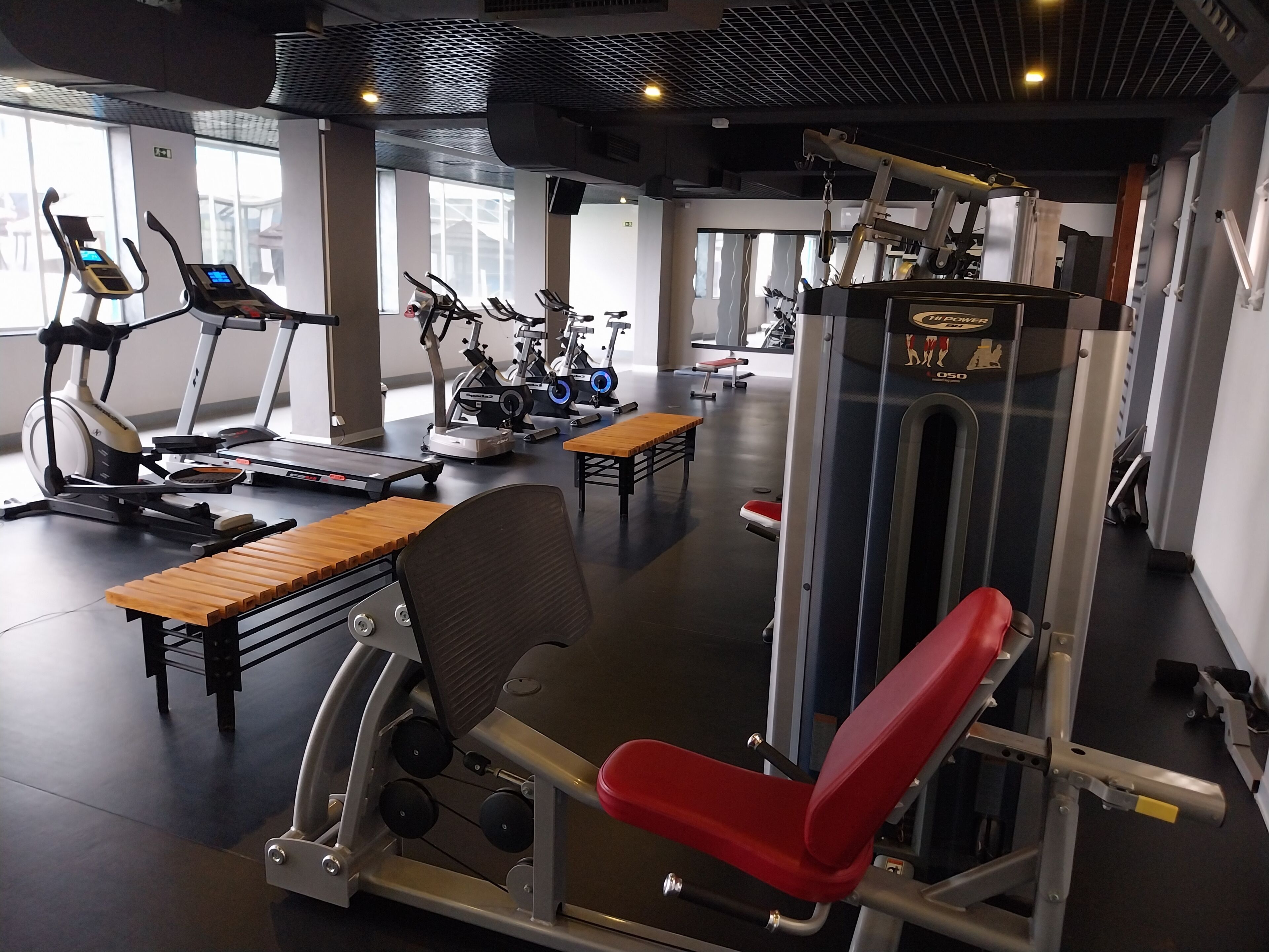 Academia com diversos equipamentos de exercícios, incluindo esteiras, bicicletas ergométricas e aparelhos de musculação.