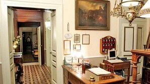 Quarto tradicional com escrivaninha de madeira, um computador e um quadro na parede.
