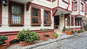 Uma fileira de edifícios de estilo europeu tradicional, com fachadas vermelhas e brancas, degraus de tijolo e plantas em vasos ao longo da rua.
