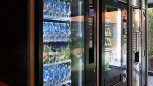 Uma fileira de máquinas automáticas com diversas bebidas e lanches.