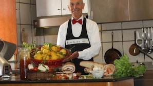 Um chef numa cozinha com uma cesta de limões, um pão e vários vegetais sobre o balcão.